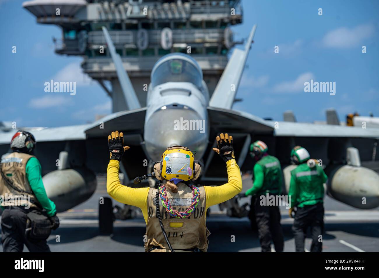 USS Nimitz, International Waters. 21 April, 2023. A U.S. Navy flight deck crew sailor directs a ...