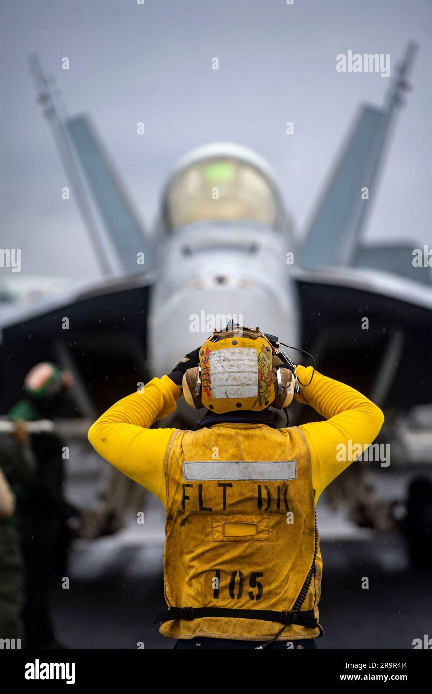 USS Nimitz, International Waters. 08 May, 2023. A U.S. Navy flight deck crew sailor directs a F ...