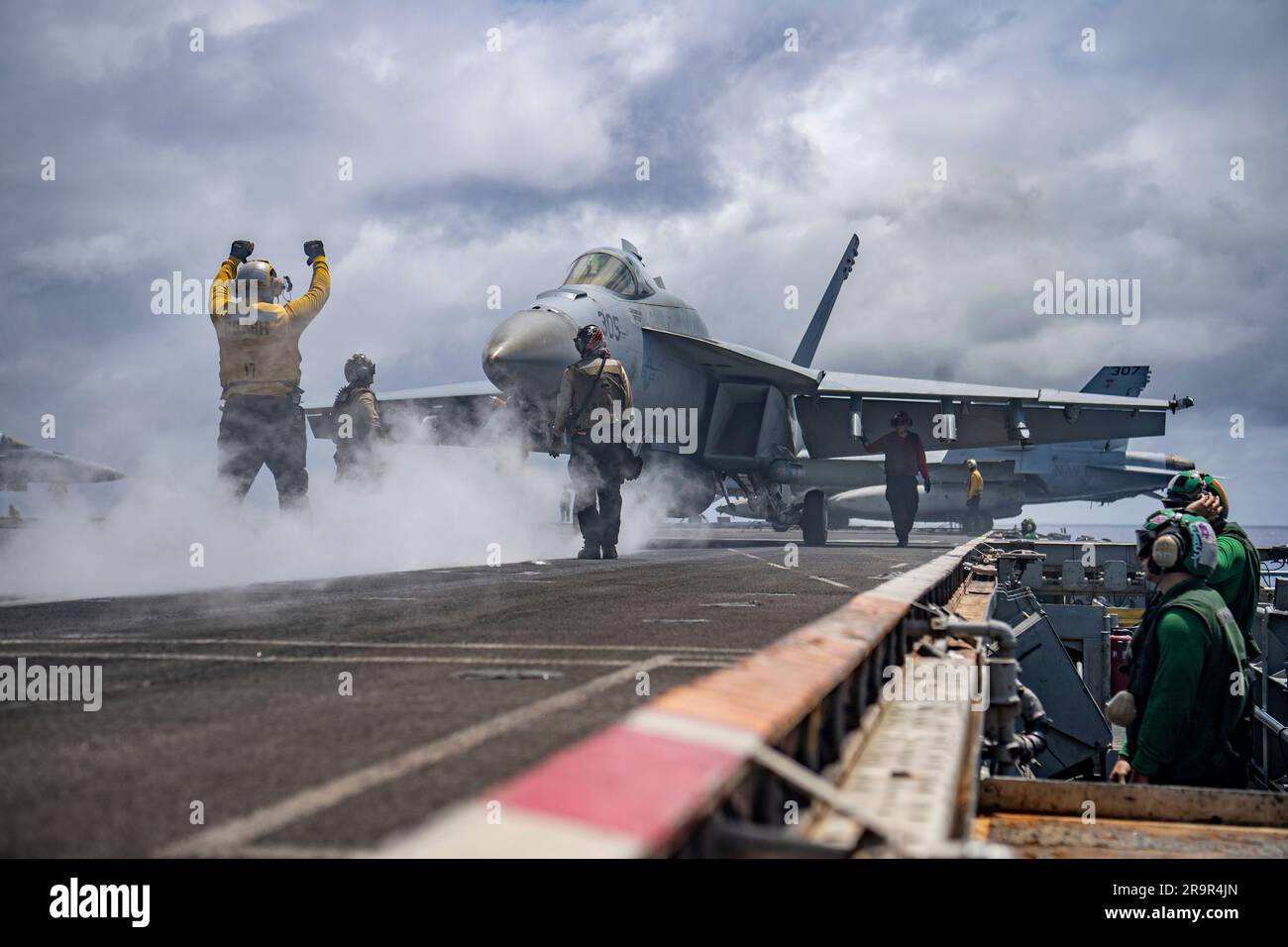 USS Nimitz, International Waters. 31 May, 2023. A U.S. Navy flight deck crew sailor directs a F ...