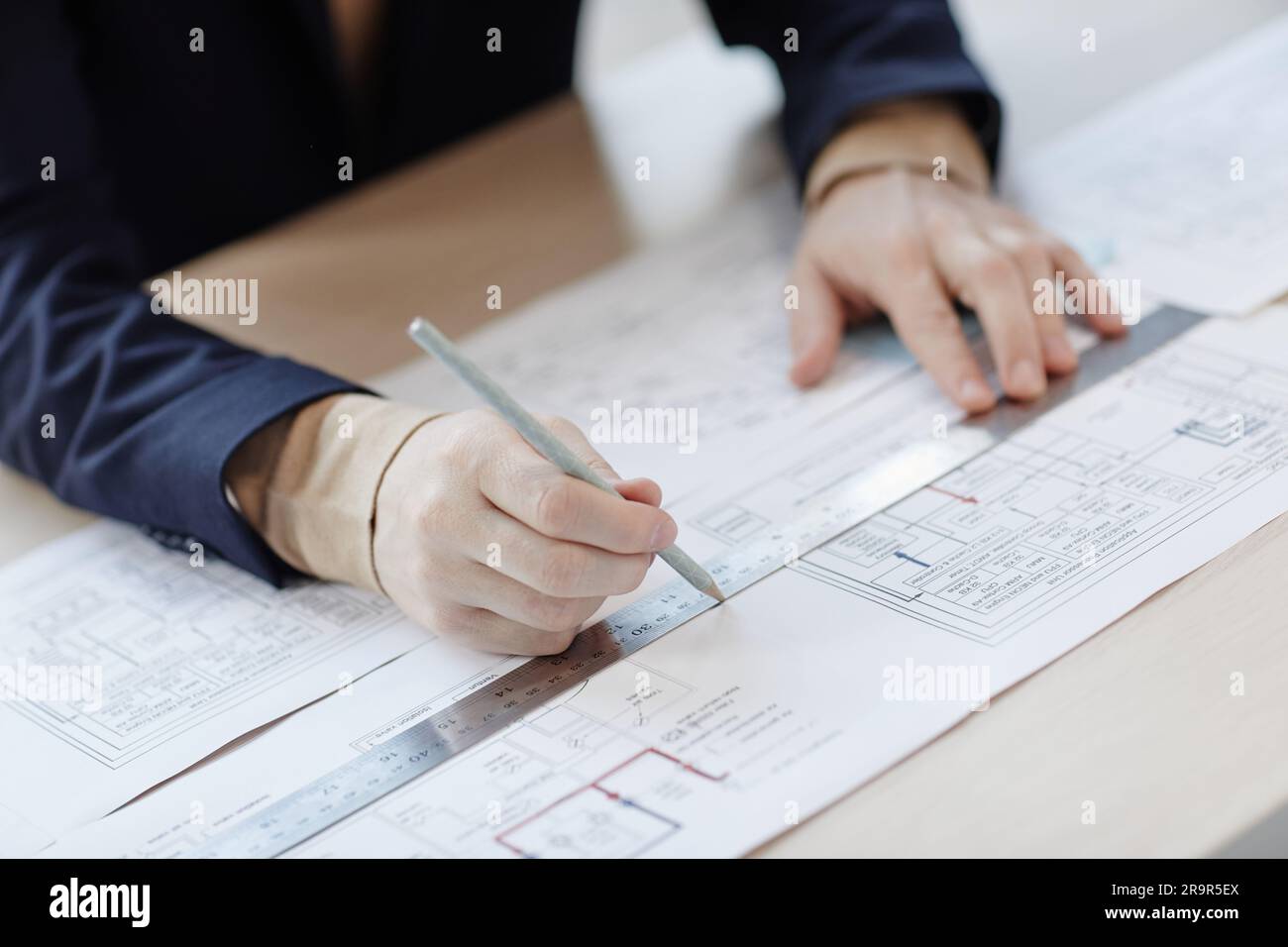 Closeup engineer at workstation drawing blueprints and plans by hand ...