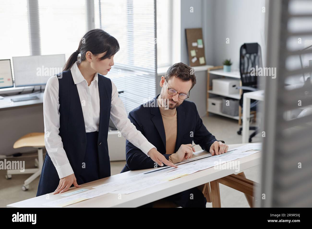Portrait of two engineers at workstation drawing blueprints and plans ...
