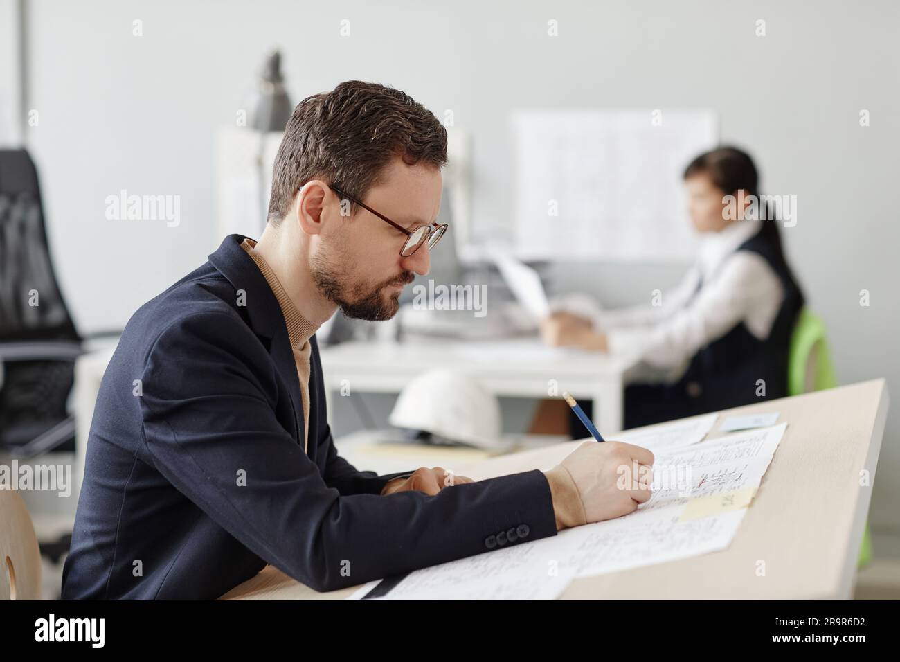 Side view portrait of male engineer at drawing blueprints and plans at ...