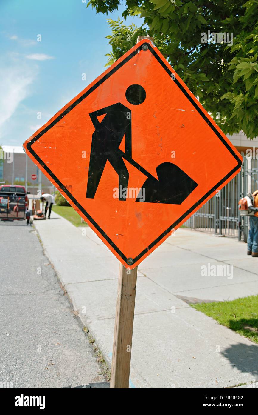 A yellow and black construction sign standing on a street, warning of a ...