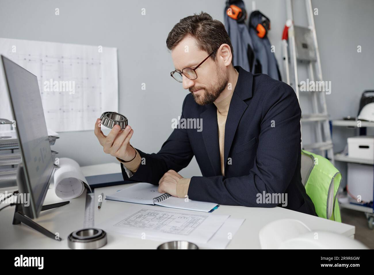 Portrait of bearded mechanical engineer holding machine part at ...
