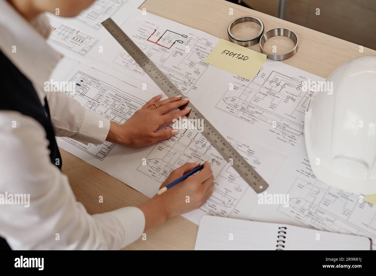 Top view of female engineer drawing blueprints and plans at workstation ...
