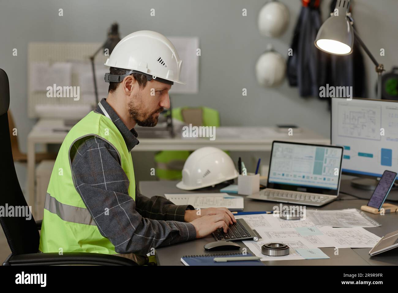 Side view portrait of male engineer wearing hardhat at workplace in ...