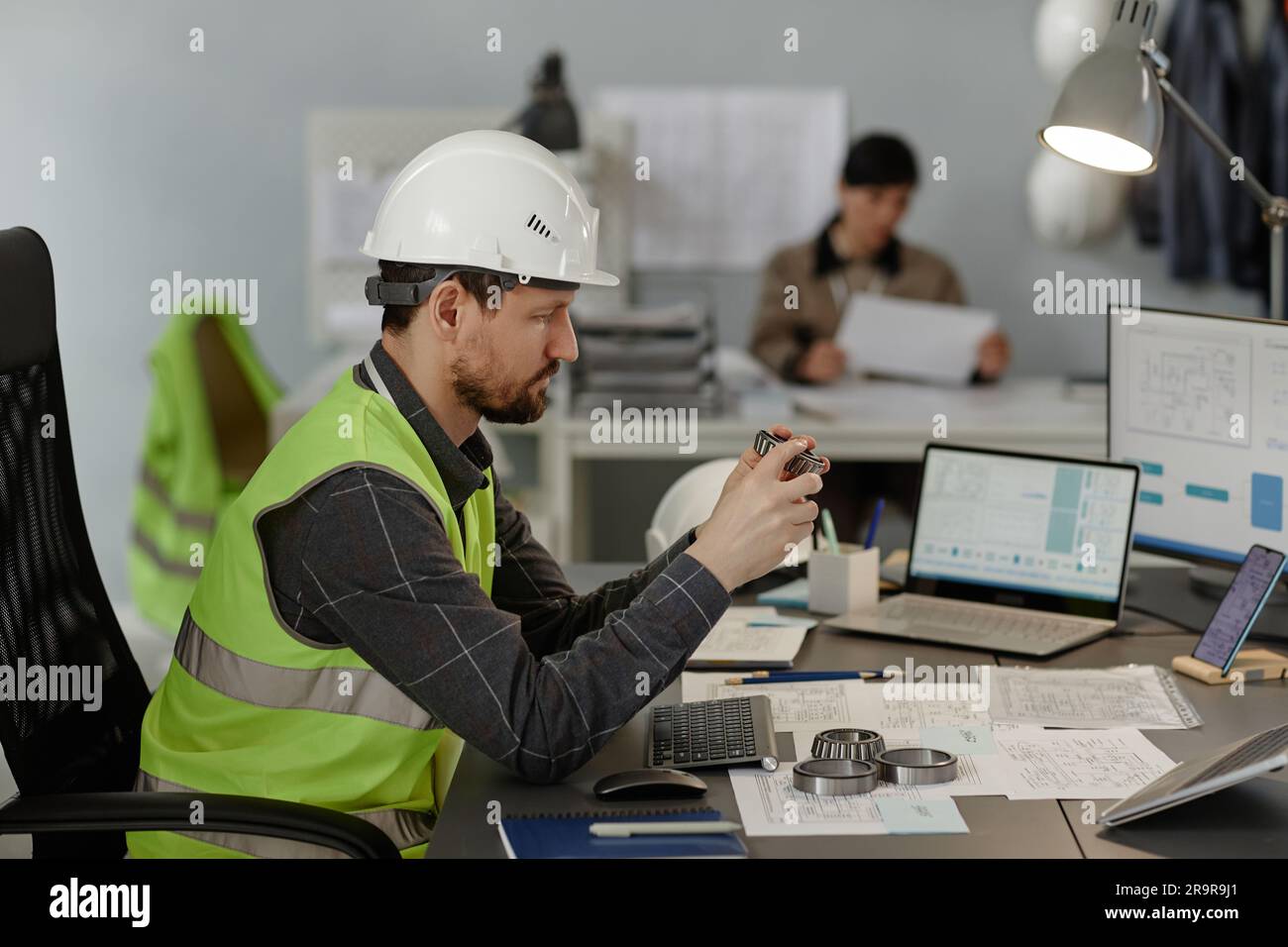 Side view portrait of male engineer holding steel bearing machine part ...