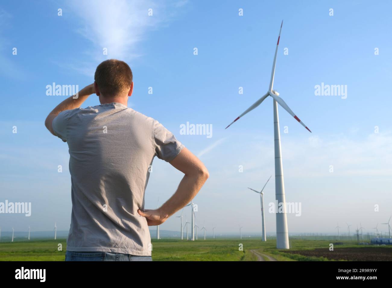 The man stands with his back and looks at the wind turbine. Wind Energy ...