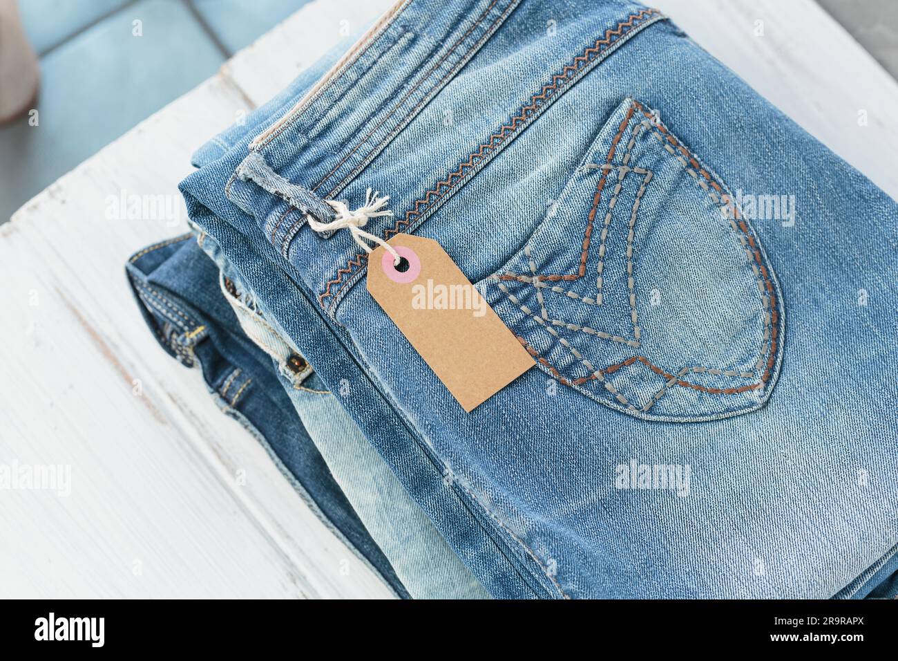 Stack of blue jeans and empty craft paper tag on white background Stock ...