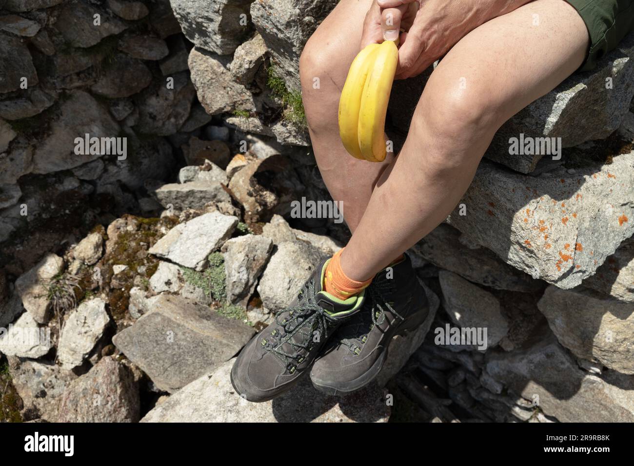 Men's feet in mountain boots and hands with bananas on a short rest in ...