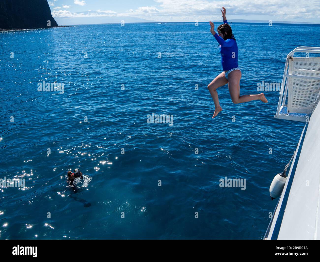 People joyfully jump off a boat into the warm clear waters of the ...