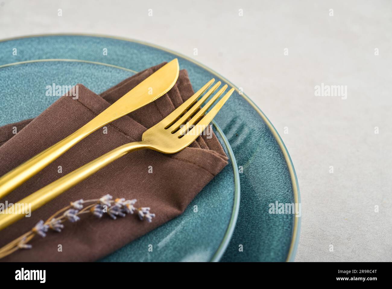 Modern minimal table place setting with blue plates and golden cutlery ...