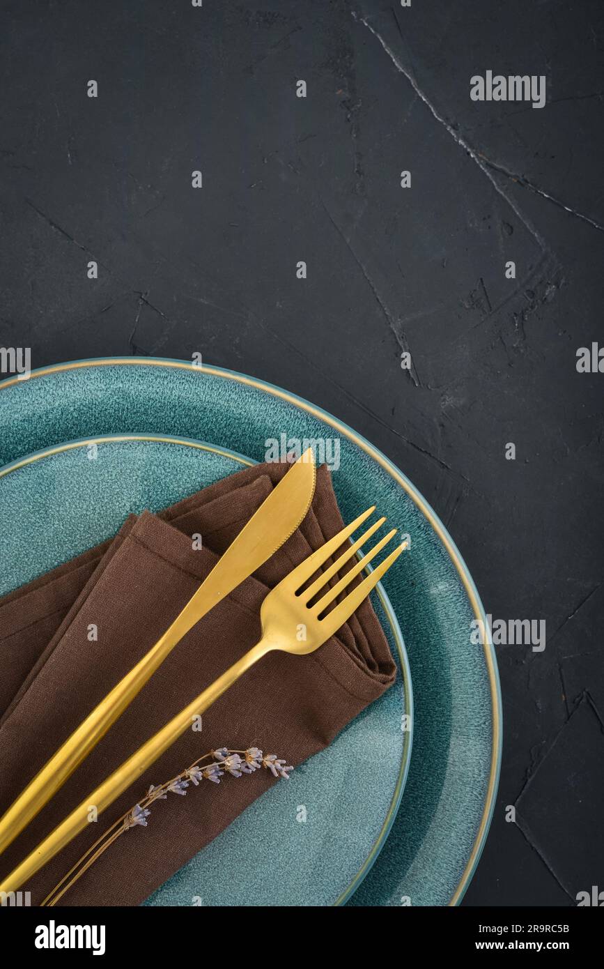 Modern minimal table place setting with blue plates and golden cutlery ...