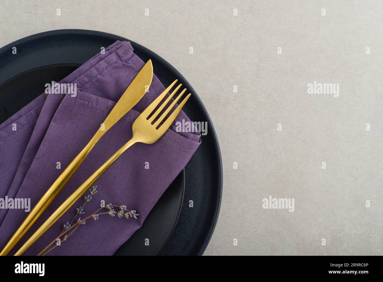 Modern minimal table place setting with black plates and golden cutlery ...
