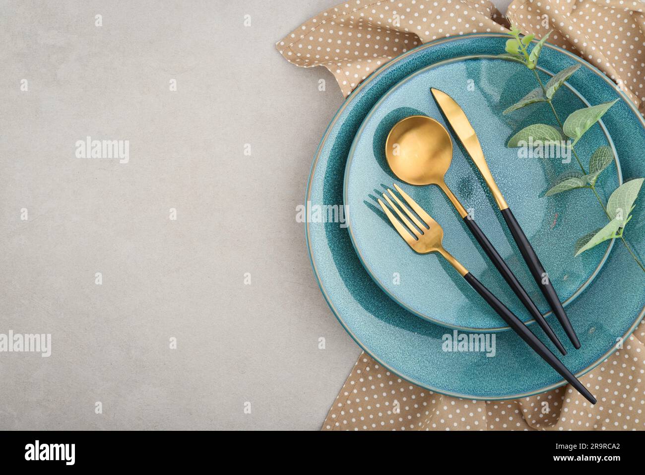 Modern minimal table place setting with blue plates and golden cutlery ...