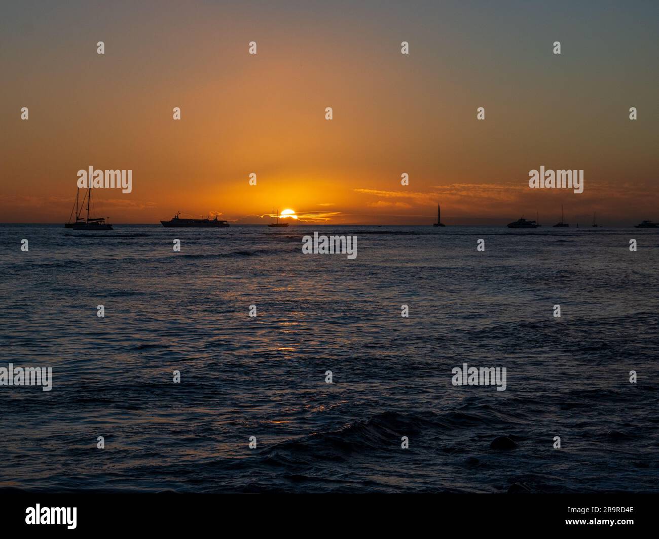 Sunset over the Pacific Ocean as seen from a Maui beach glows bright ...
