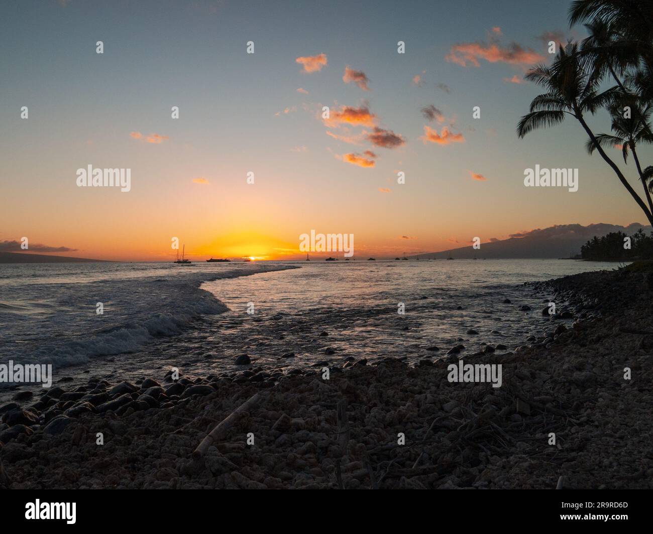 Sunset over the Pacific Ocean as seen from a Maui beach glows bright ...