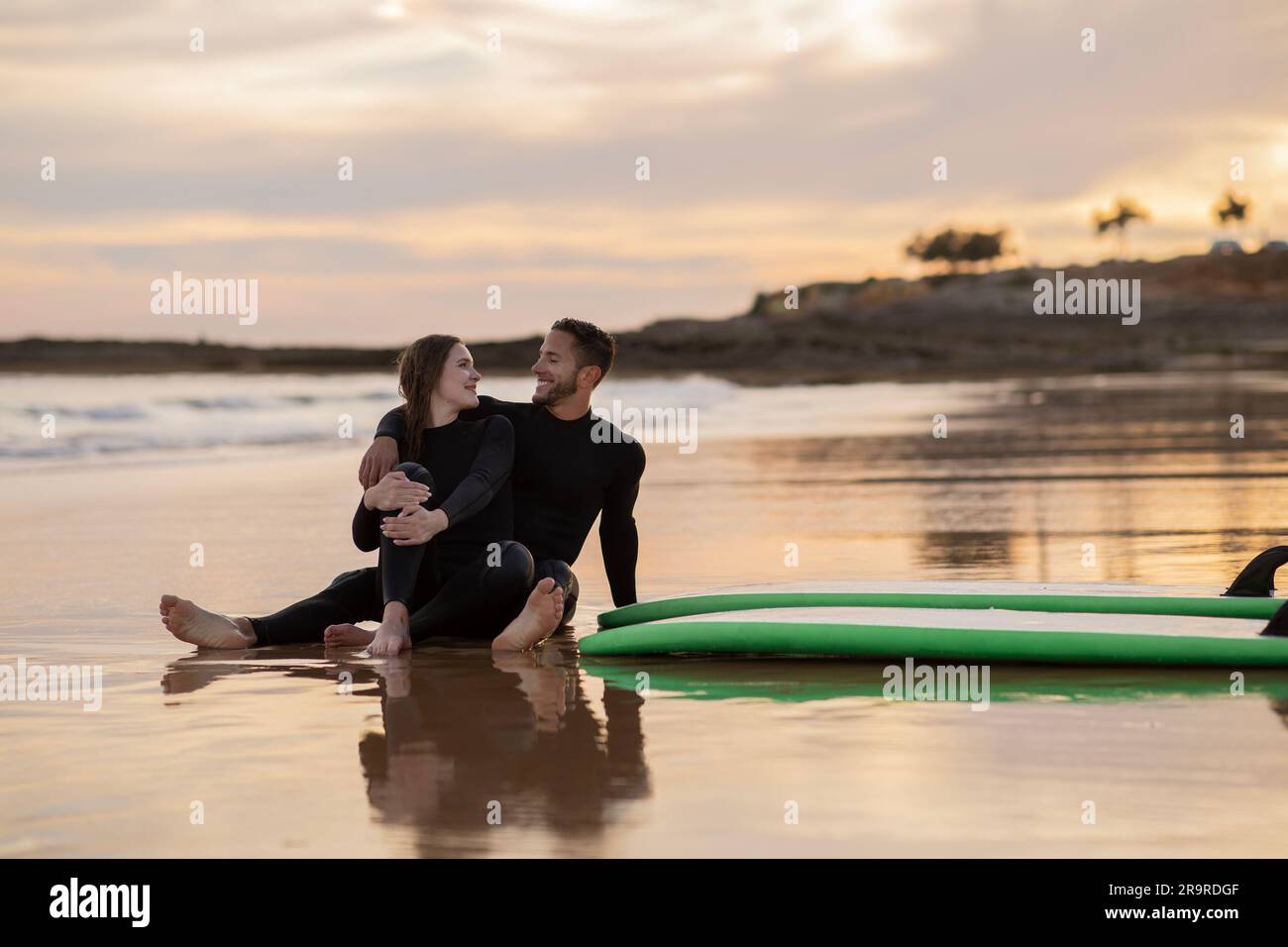 Young woman with surfboard sitting on beach at sunset hi-res stock ...