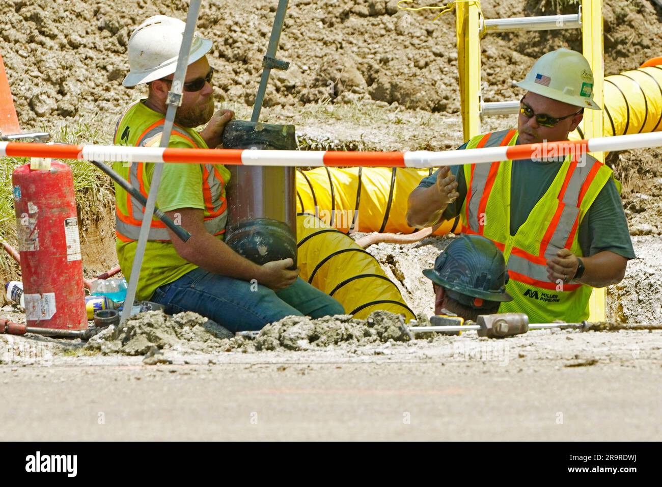 Utility workers attempt to stay in the shade as they work on a gas line ...