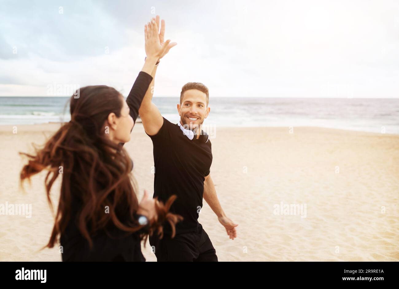 Smiling couple running giving high five on beach near ocean Stock Photo ...