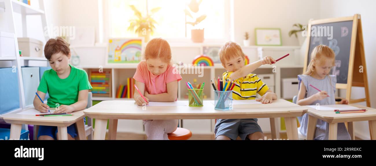 Group of children sitting in the classroom and drawing Stock Photo - Alamy