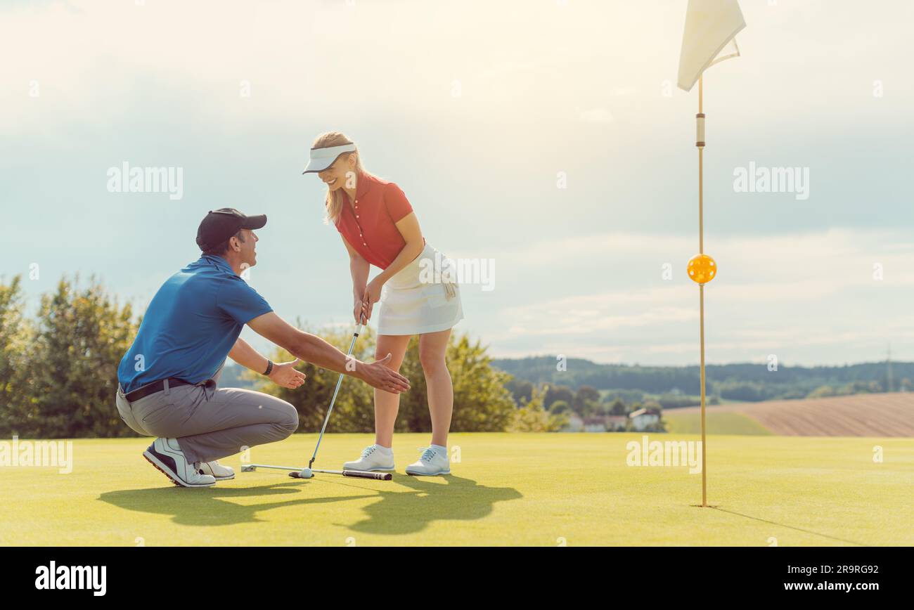 Pro on golf course teaching a woman how to put Stock Photo - Alamy