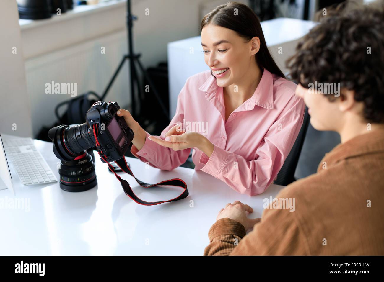 Happy woman photographer showing photos after shooting, talking after ...