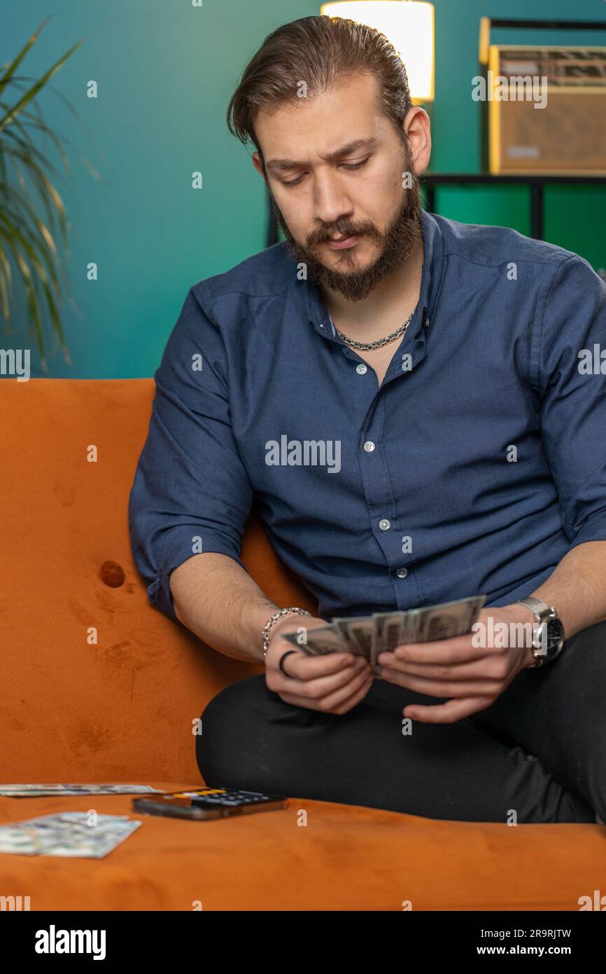 Planning budget. Rich lebanese man counting money cash use smartphone ...