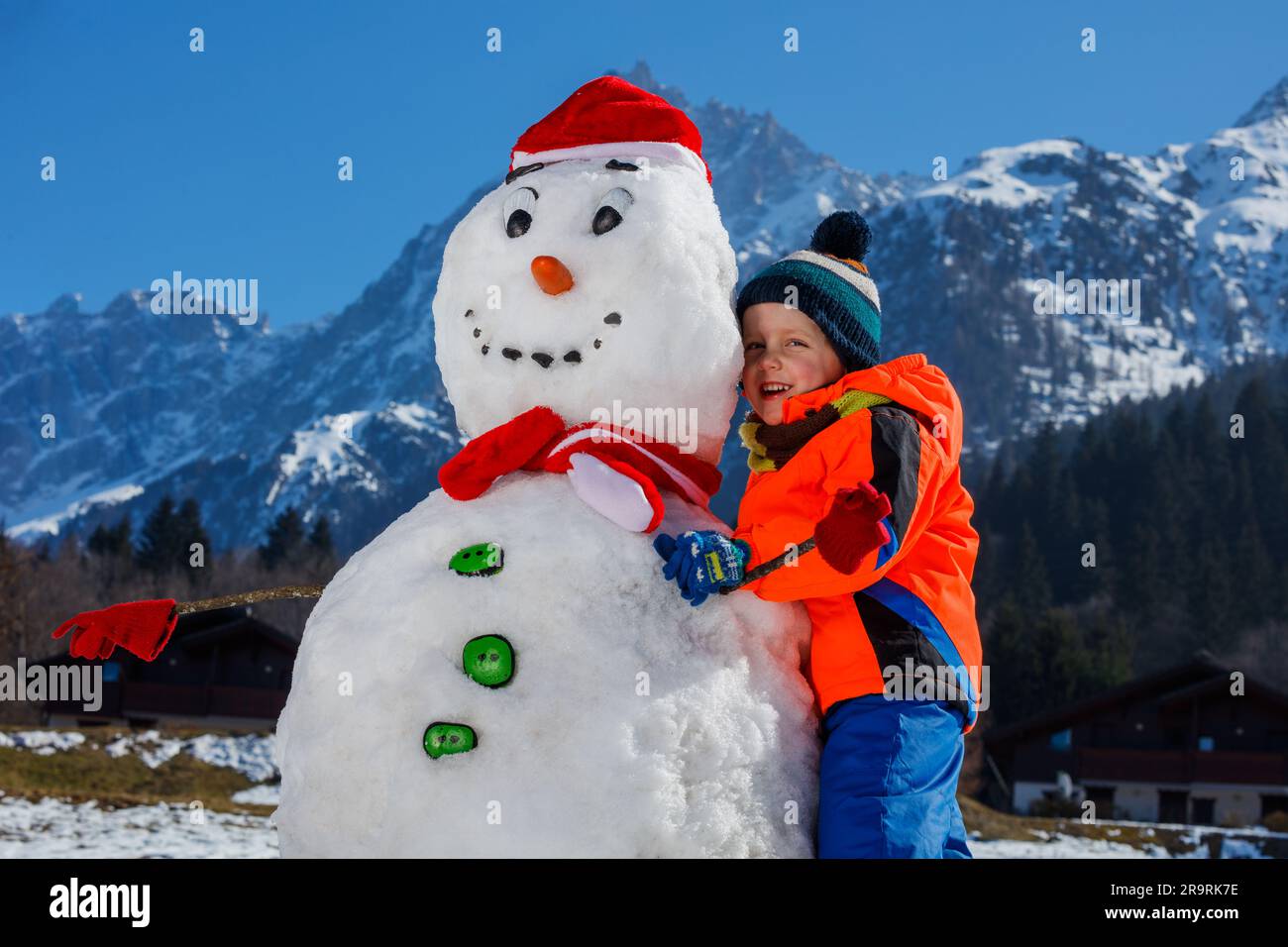 Little boy hug and play with cute freshly build snowman Stock Photo - Alamy
