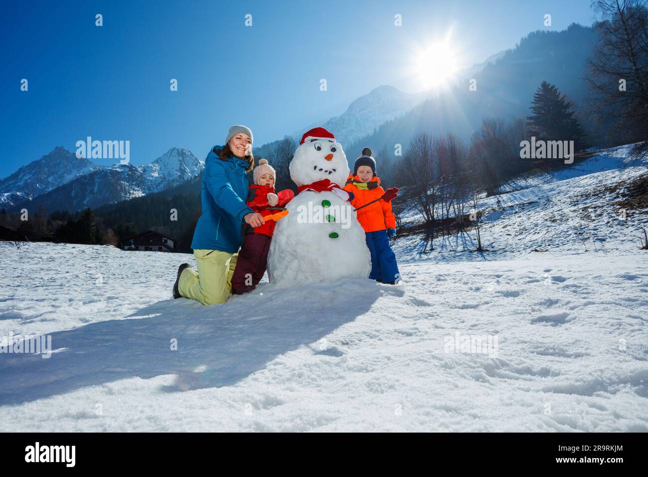 Family with mom and three kids play building snowman Stock Photo - Alamy