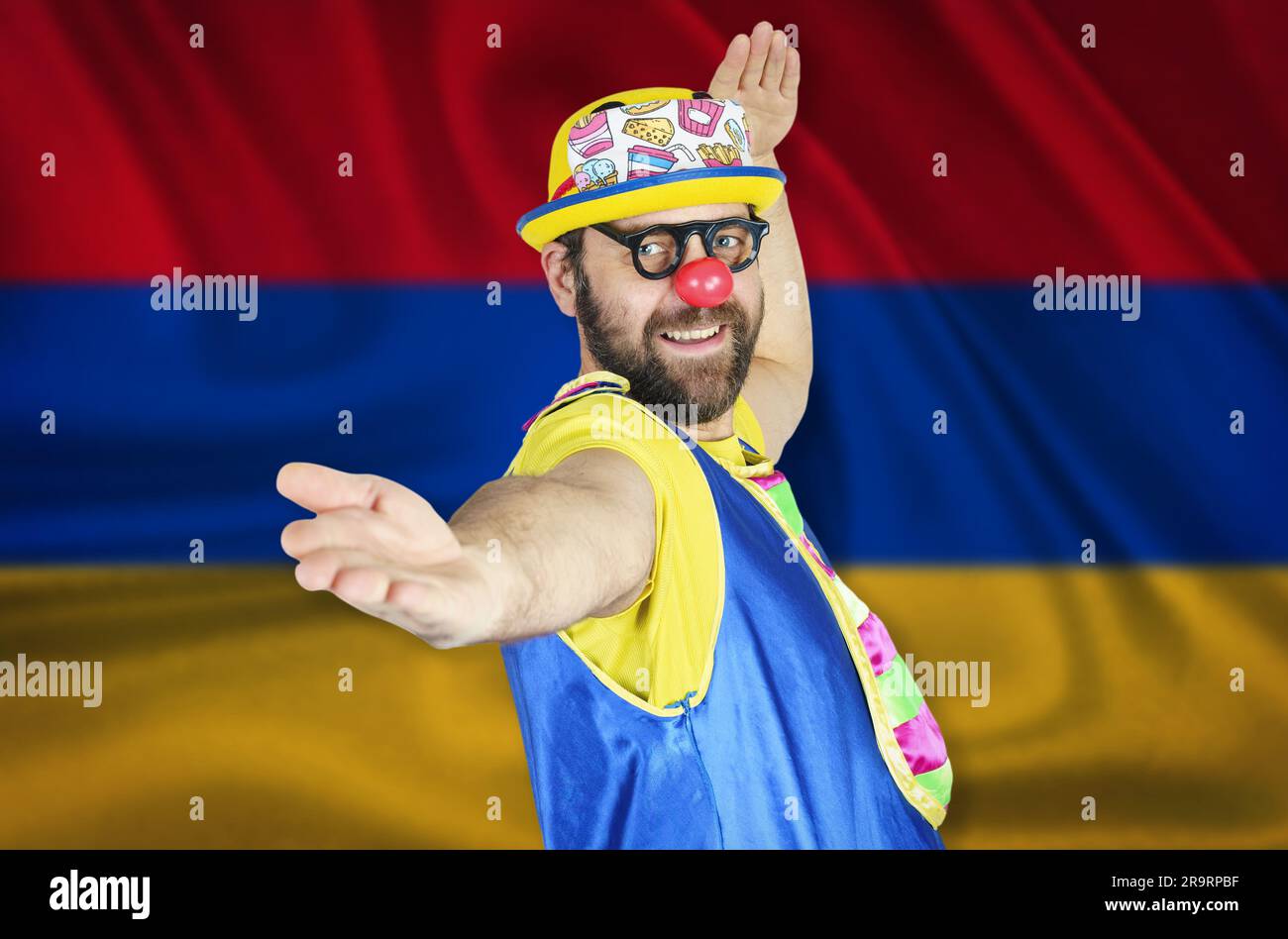 A Cheerful Clown Stands In A Welcoming Pose Against The Background Of The Flag Of Armenia Stock