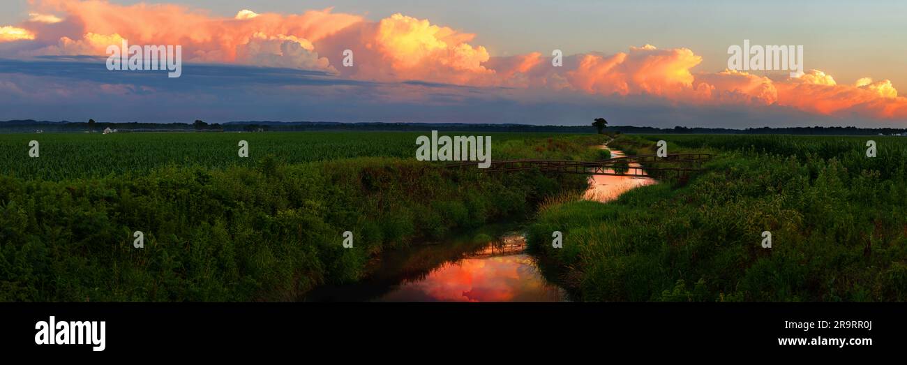 The warm colors of sunset appear in some fluffy clouds above a narrow ...