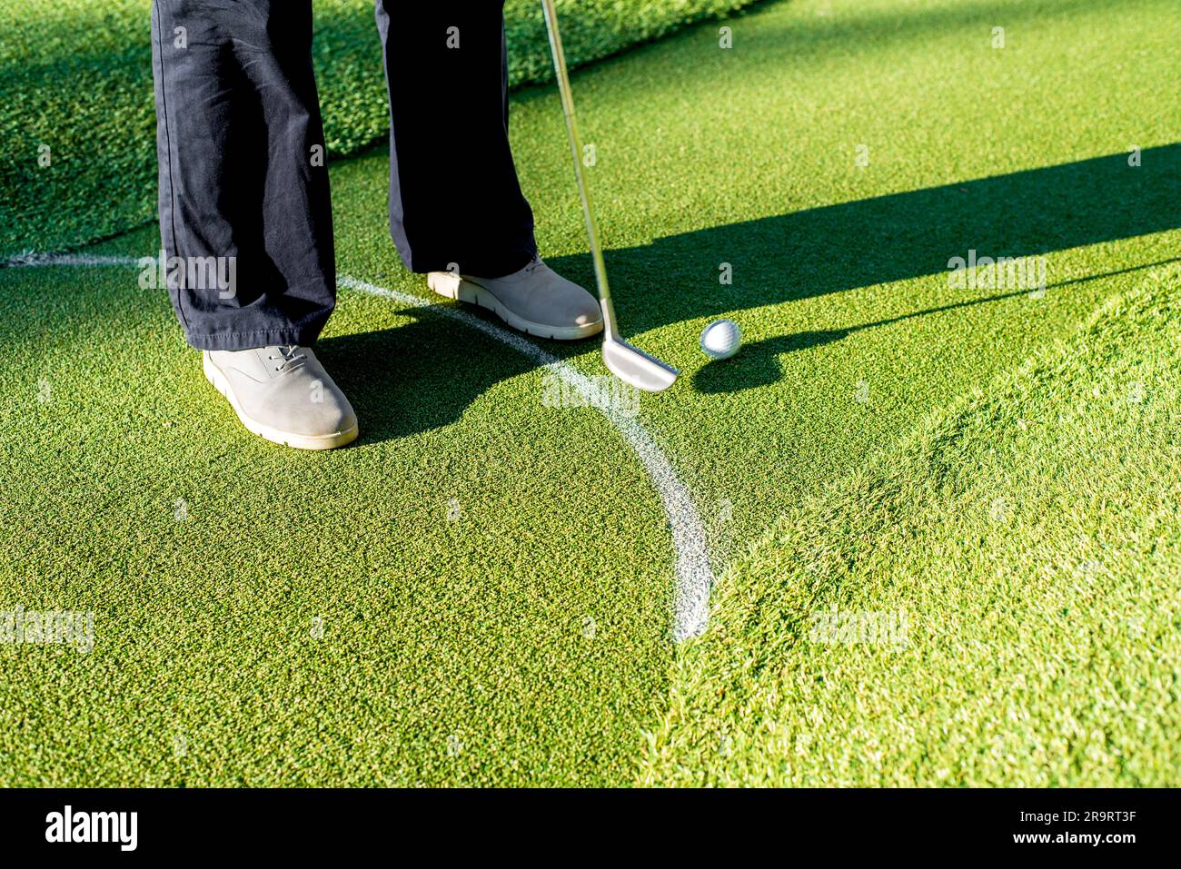 Mini Golf player with grey sneakers putting golf ball into the hole on ...