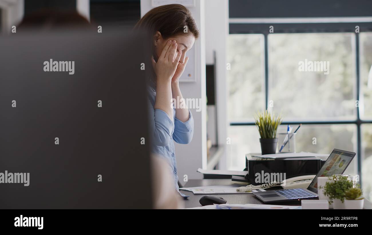 Office worker dealing with migraine and working on pc, rubbing temples ...