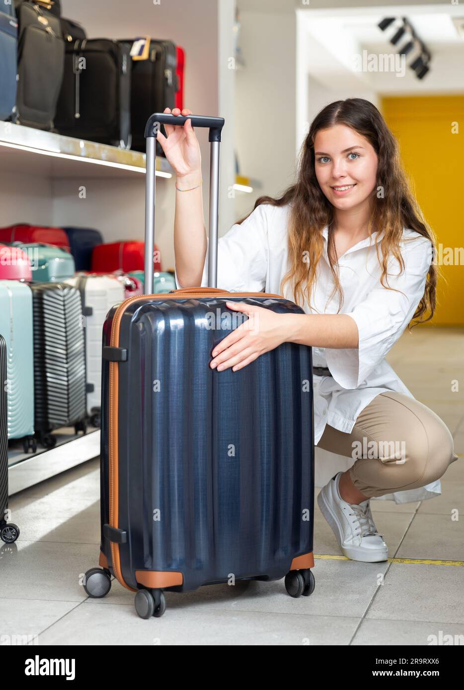 Portrait of woman picking new big plastic luggage bag with wheels Stock ...