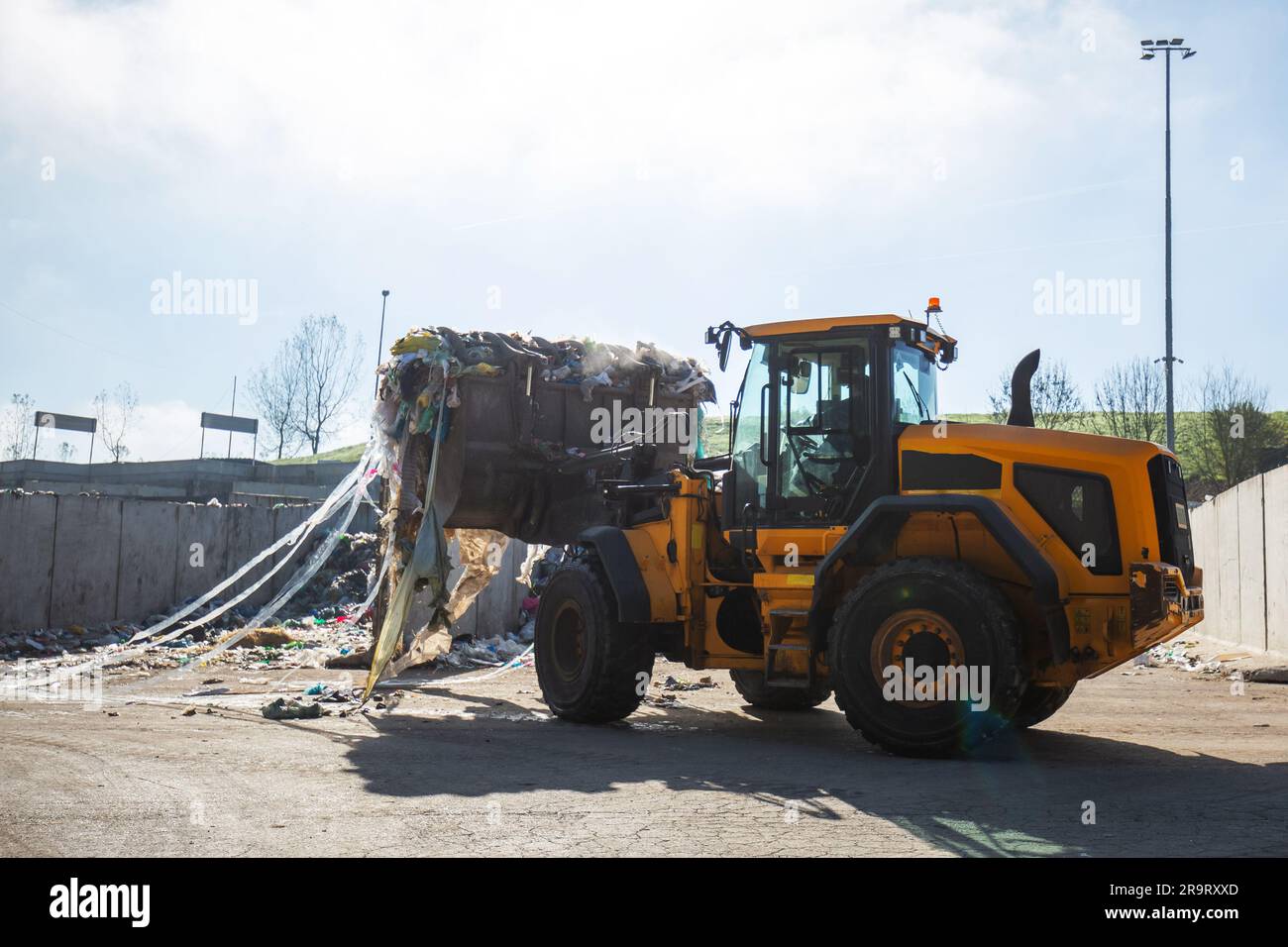 Yellow skid steer loader moving wooden waste material, shaking out a ...