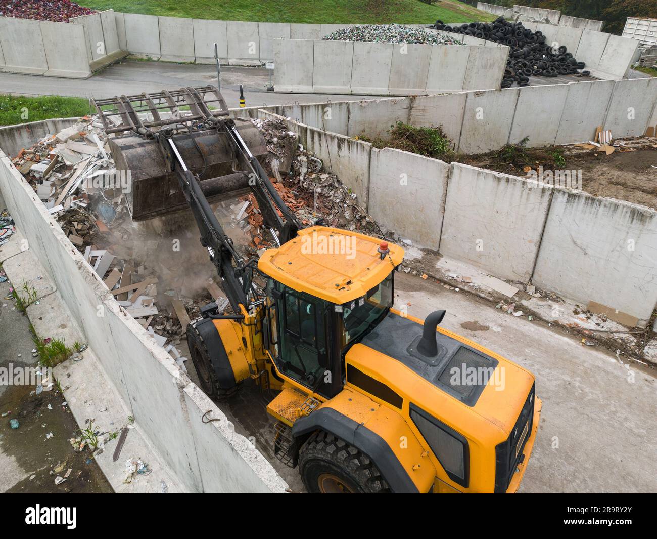 Yellow skid steer loader moving wooden waste material, shaking out a ...
