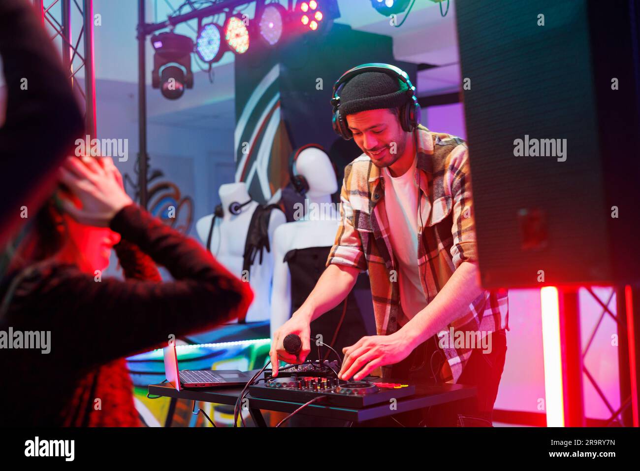 Dj in headphones using jog wheel and knobs while mixing sound with ...