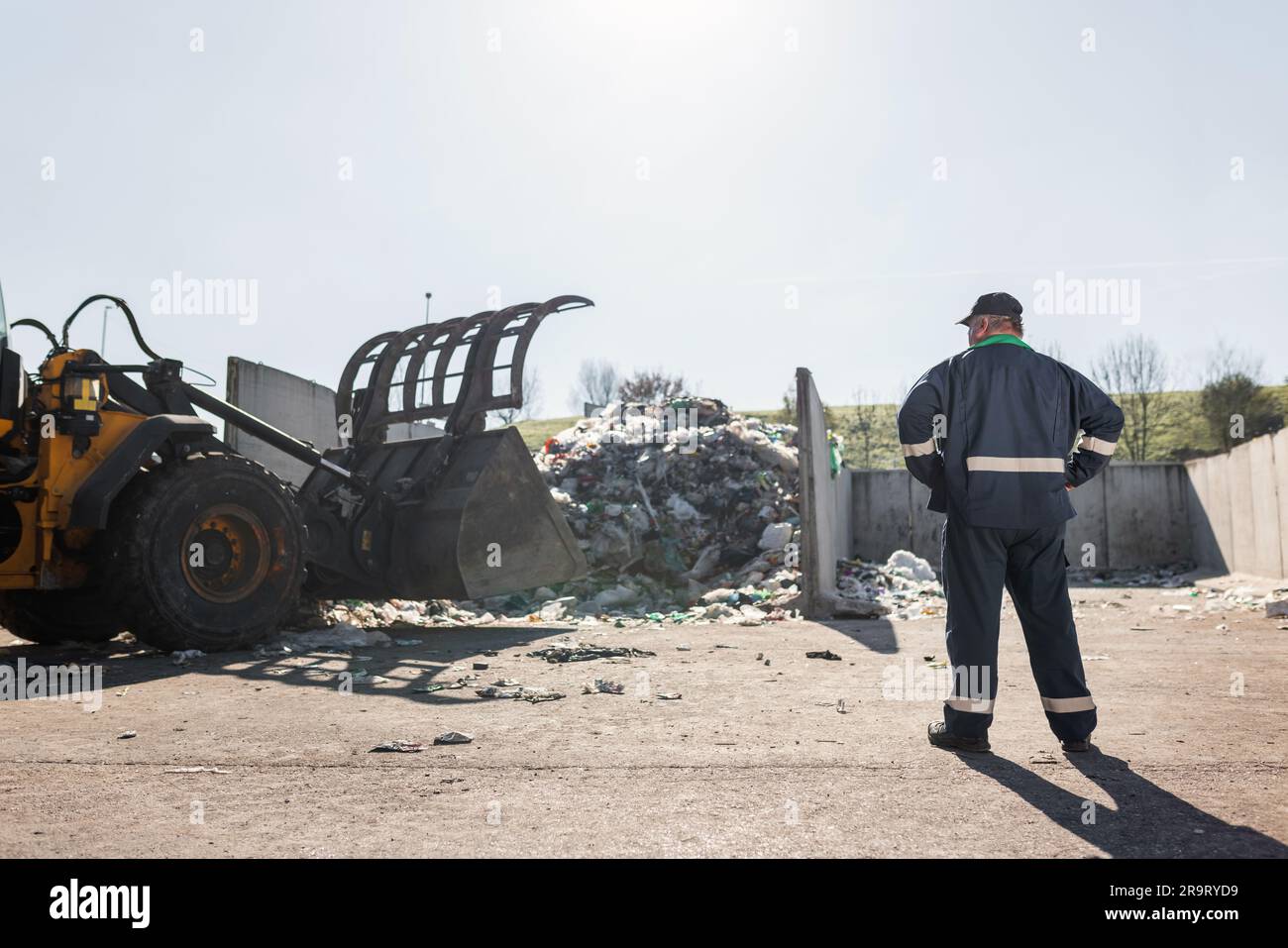 Recycling center worker, in dark blue work clothes, looking at an ...