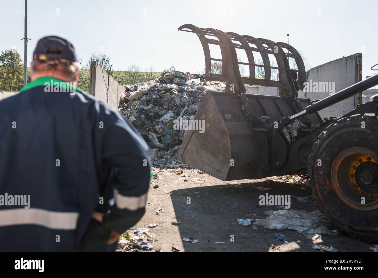 Recycling center worker, in dark blue work clothes, looking at an ...