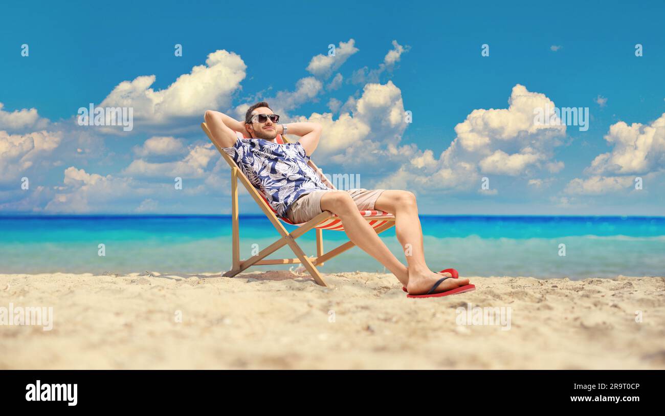 Young man sitting at a deck chair by the sea Stock Photo - Alamy