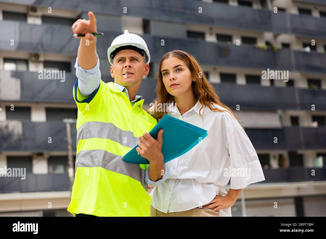Builder talking with client at construction site Stock Photo - Alamy