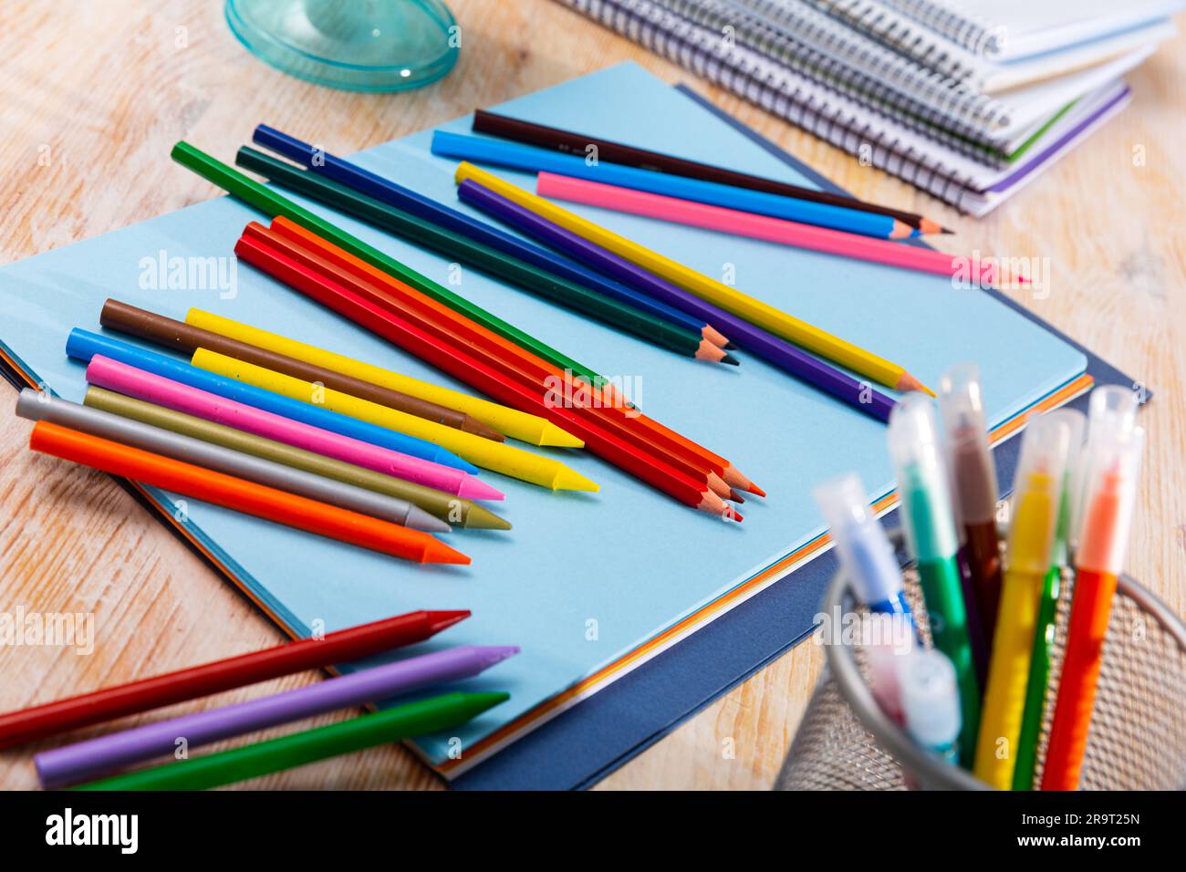 Colored pencils and sketchpads on wooden surface Stock Photo - Alamy