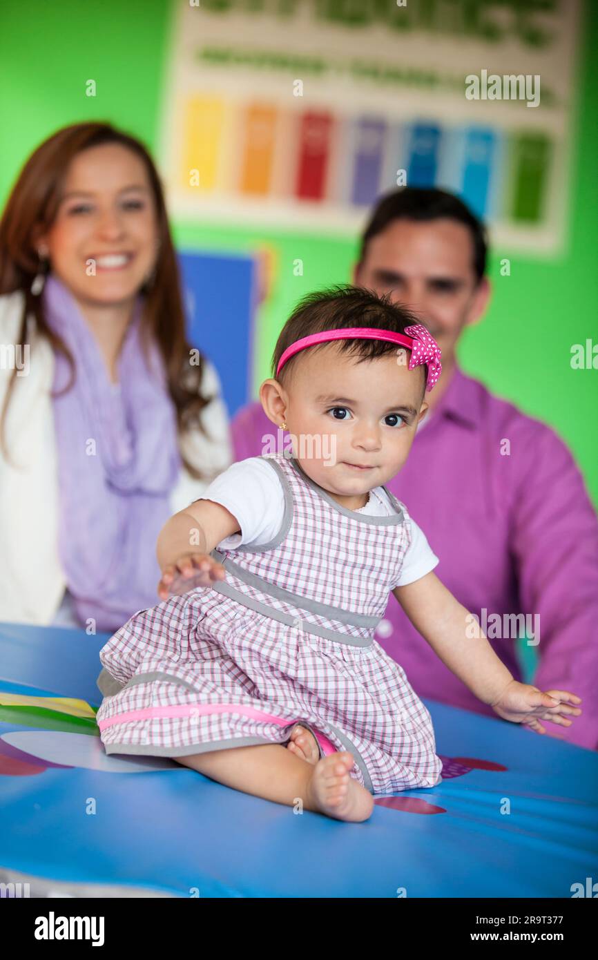 Beautiful ten months baby girl playing with her parents on background ...