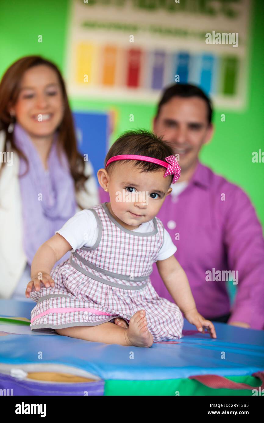 Beautiful ten months baby girl playing with her parents on background ...