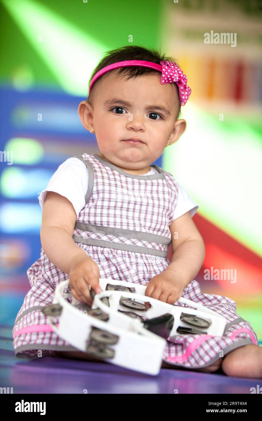 Beautiful ten months baby girl playing with a tambourine. Early ...