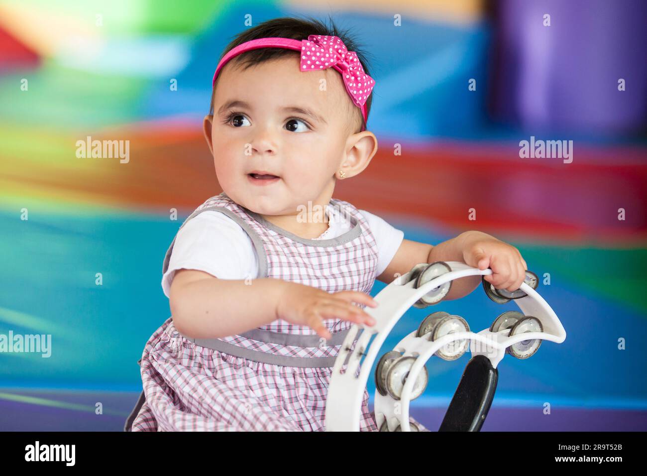 Beautiful ten months baby girl playing with a tambourine. Early ...