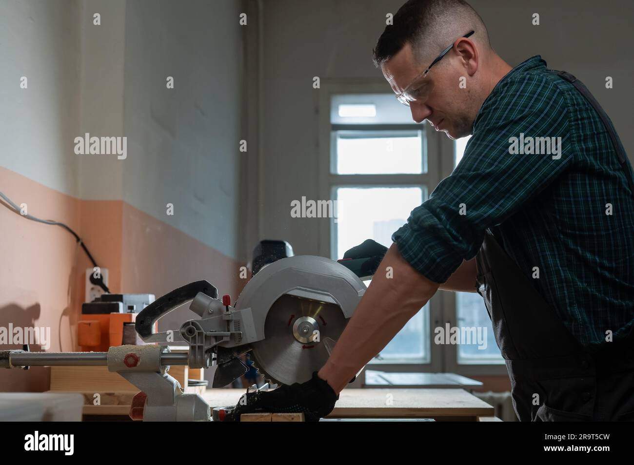 Master cuts the board with a circular saw in the workshop Stock Photo ...