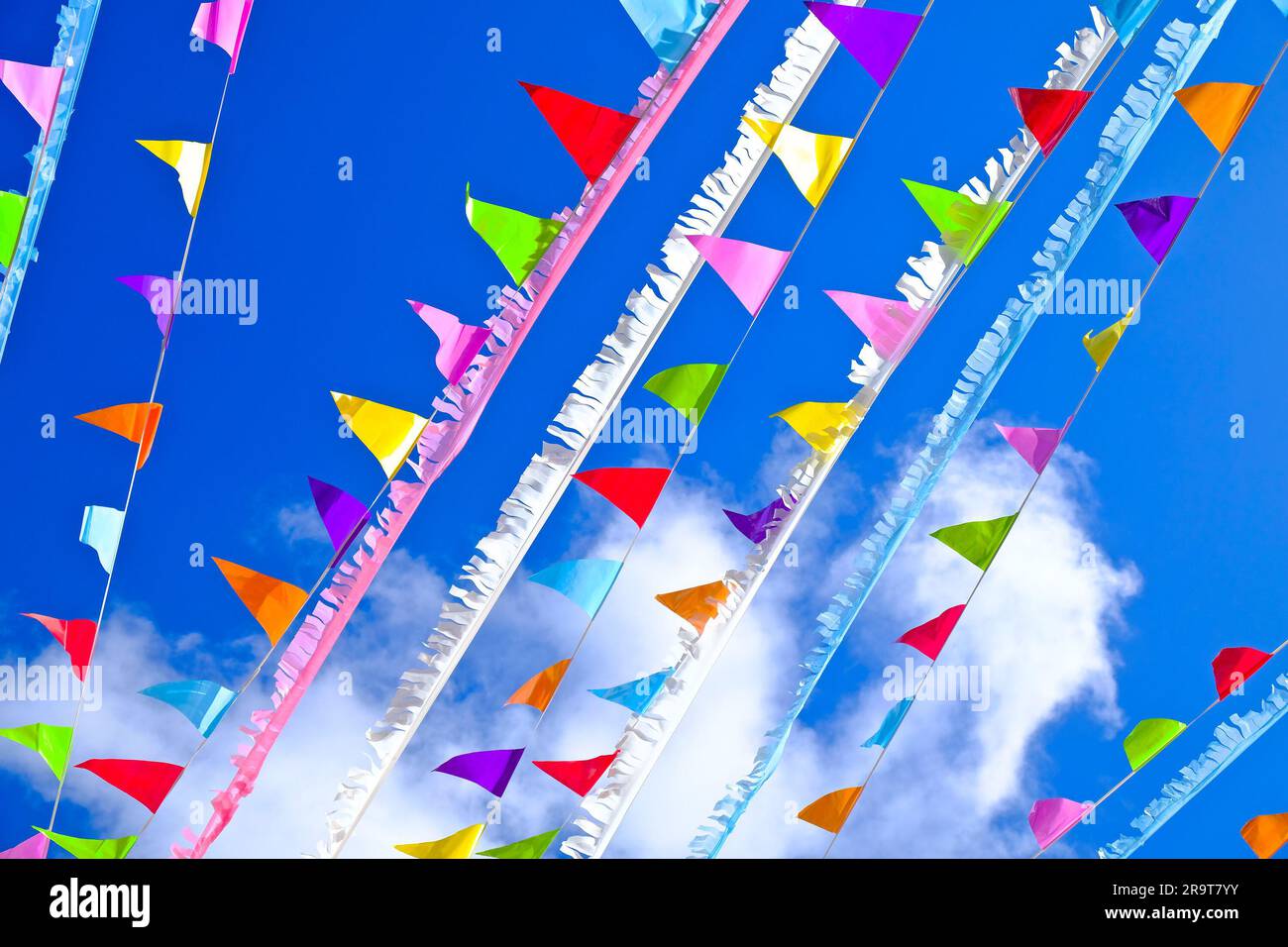Strings of rainbow colored flags and pennants on bright blue sky and ...
