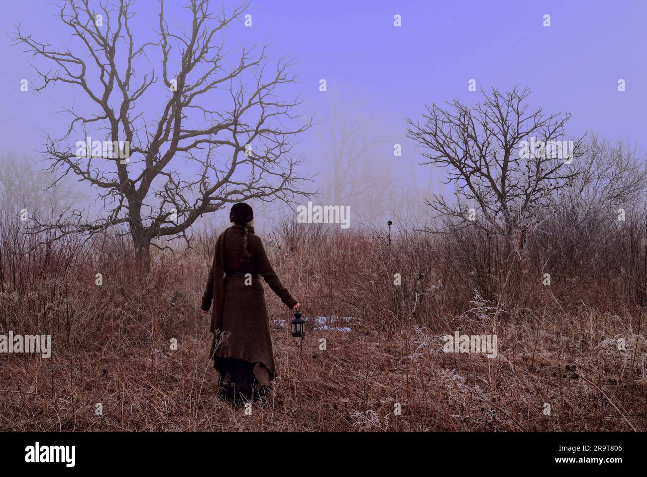 Victorian woman walking with lantern through winter wooded marsh. Early ...